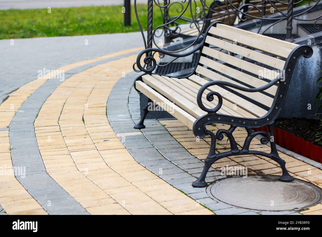A beautifully crafted wooden park bench is situated on a gently curved ...