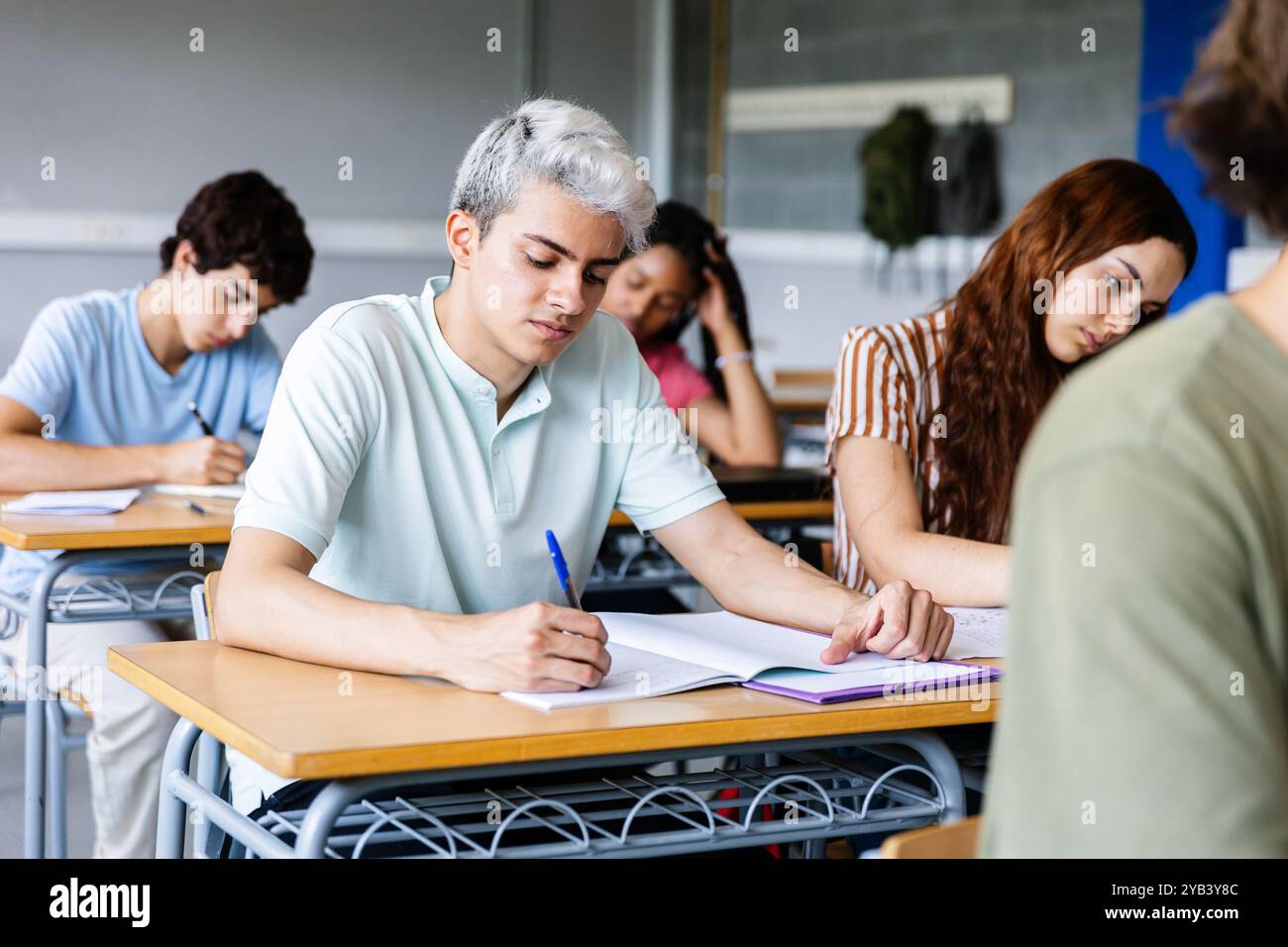 Students taking notes while listening teacher in classroom at high ...
