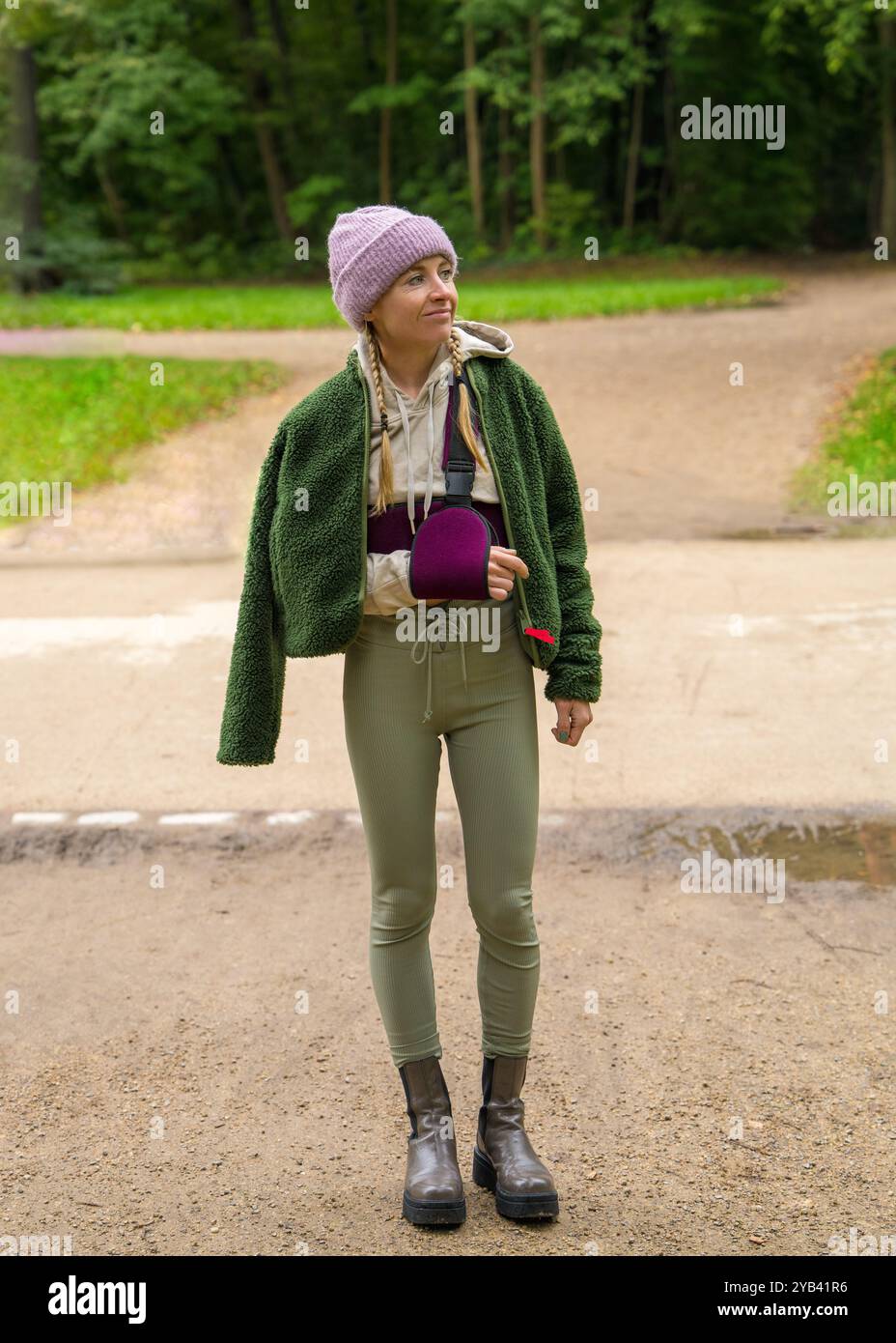 Young woman with broken arm slowly walking outdoors. Patient wears ...
