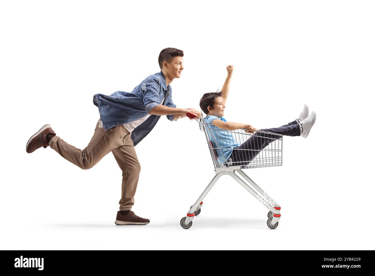 Teenager pushing a younger boy inside a shopping cart isolated on white ...