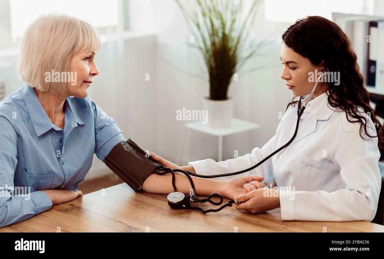 Female nurse checking blood pressure of mature woman Stock Photo - Alamy
