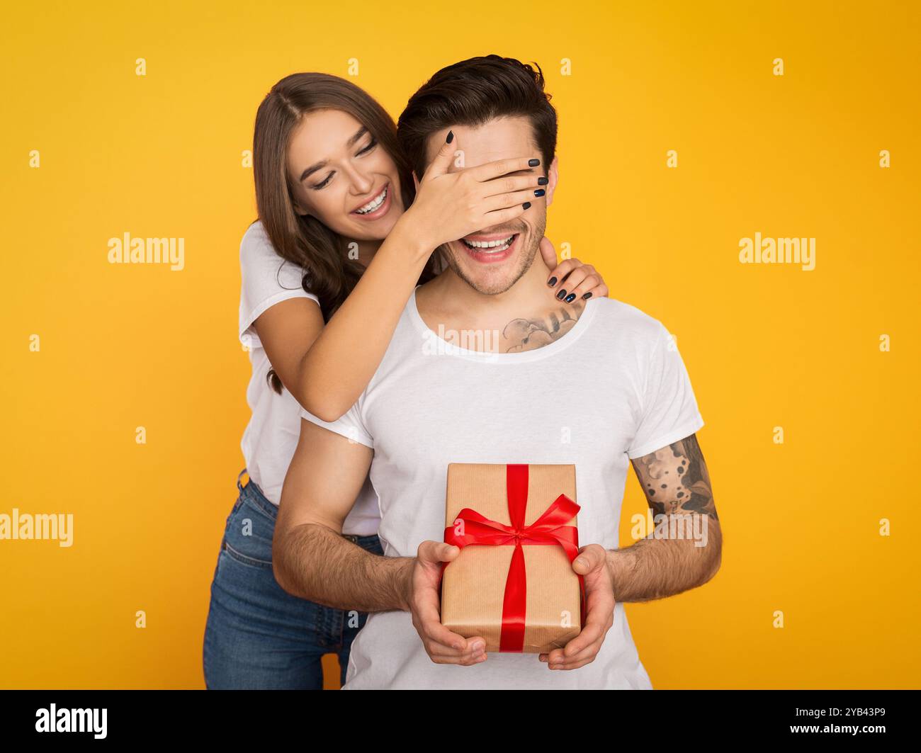 Girl covering boyfriend eyes and giving him present Stock Photo - Alamy