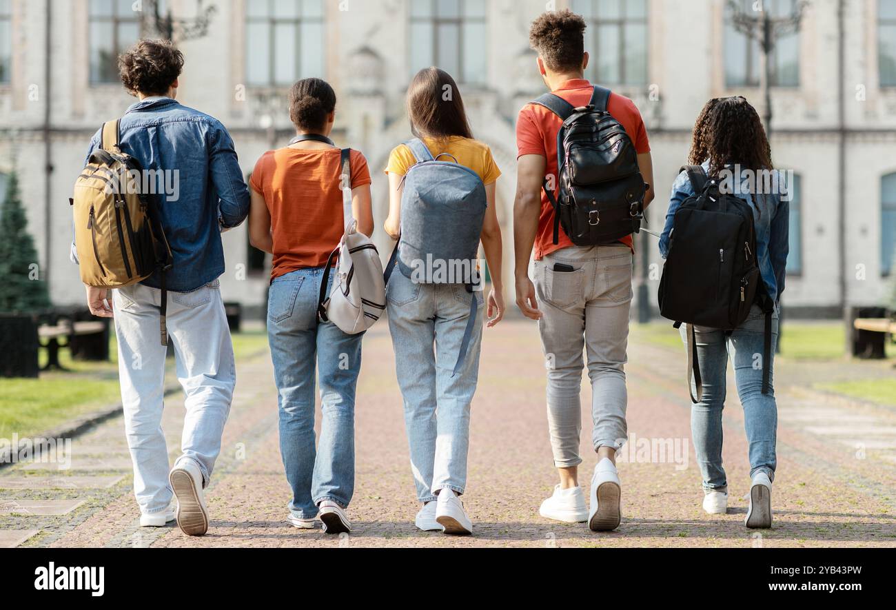 Group of five students with backpacks walking at university campus ...