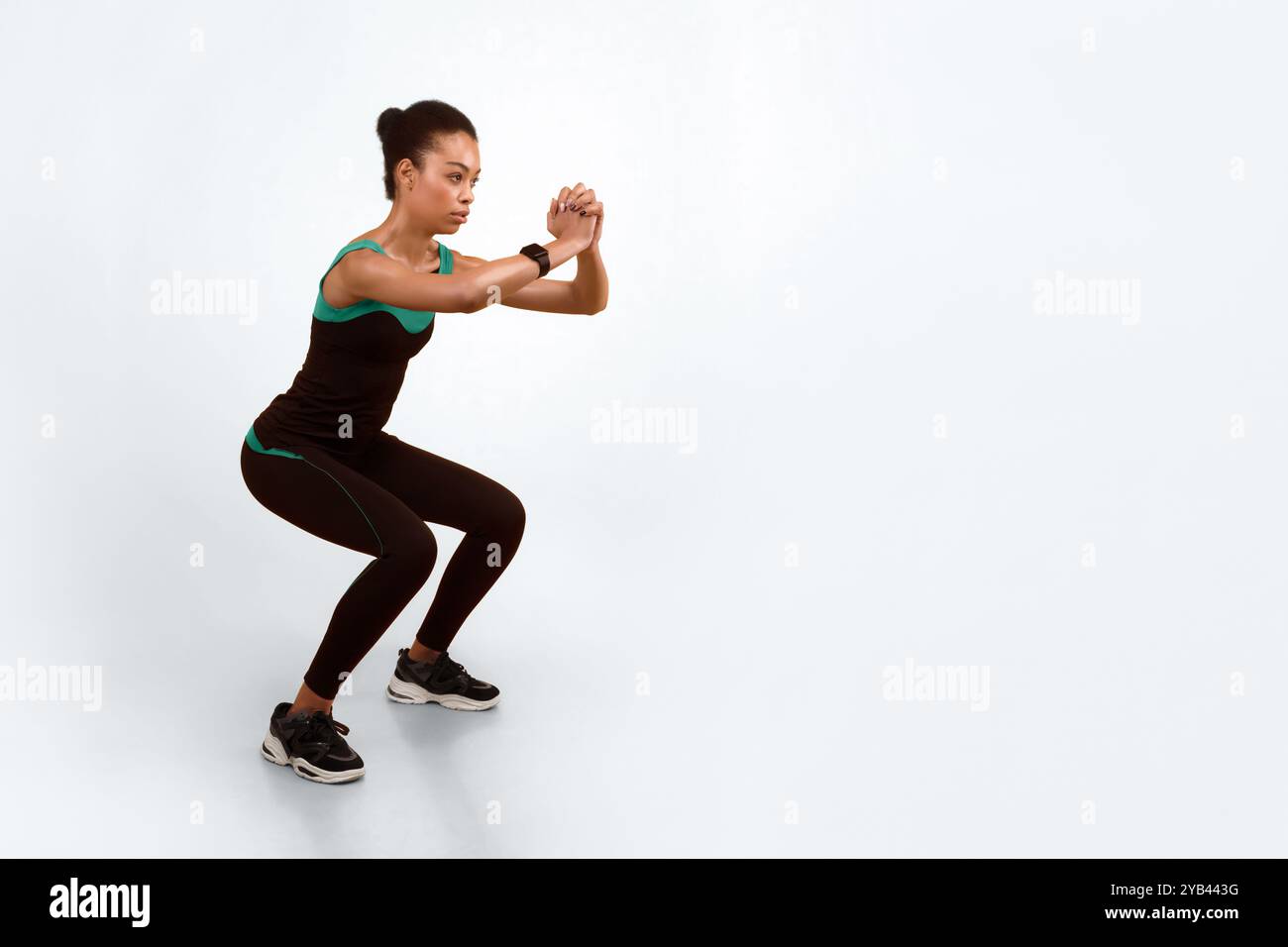 African American Woman Doing Deep Squat Exercise Over Yellow Background ...