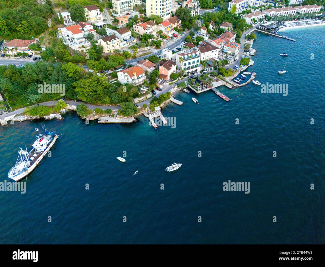 A small coastal village with piers where boats and a small ship are ...