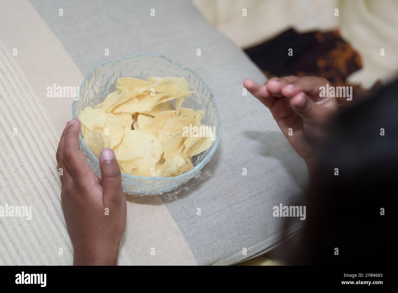 Hands reaching for crispy potato chips from a glass bowl, perfect for ...