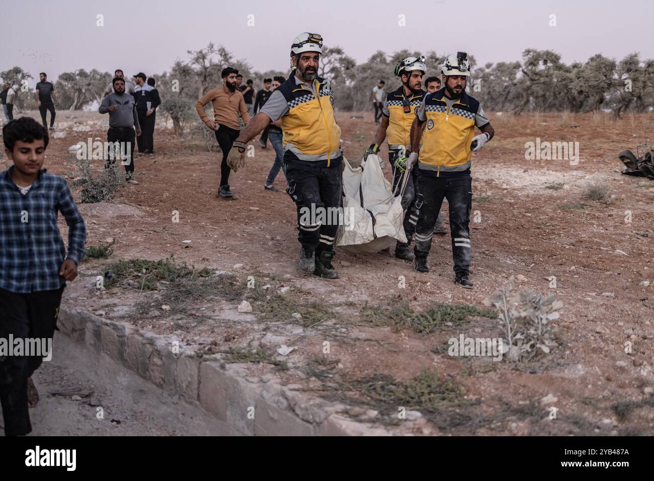 Idlib, Syria. 16th Oct, 2024. Members of the Syrian Civil Defense carry ...