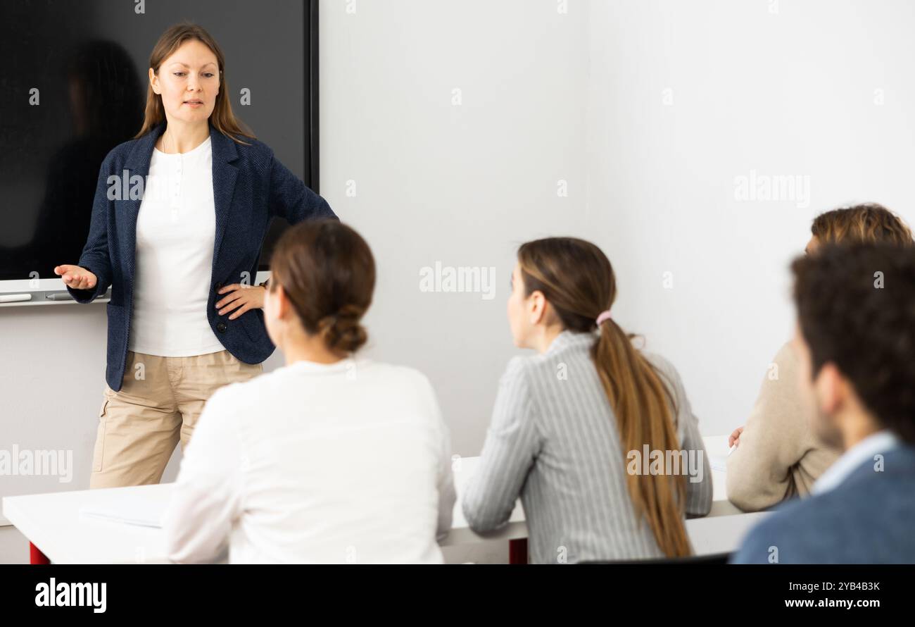 Experienced female teacher giving lecture to group of student Stock ...