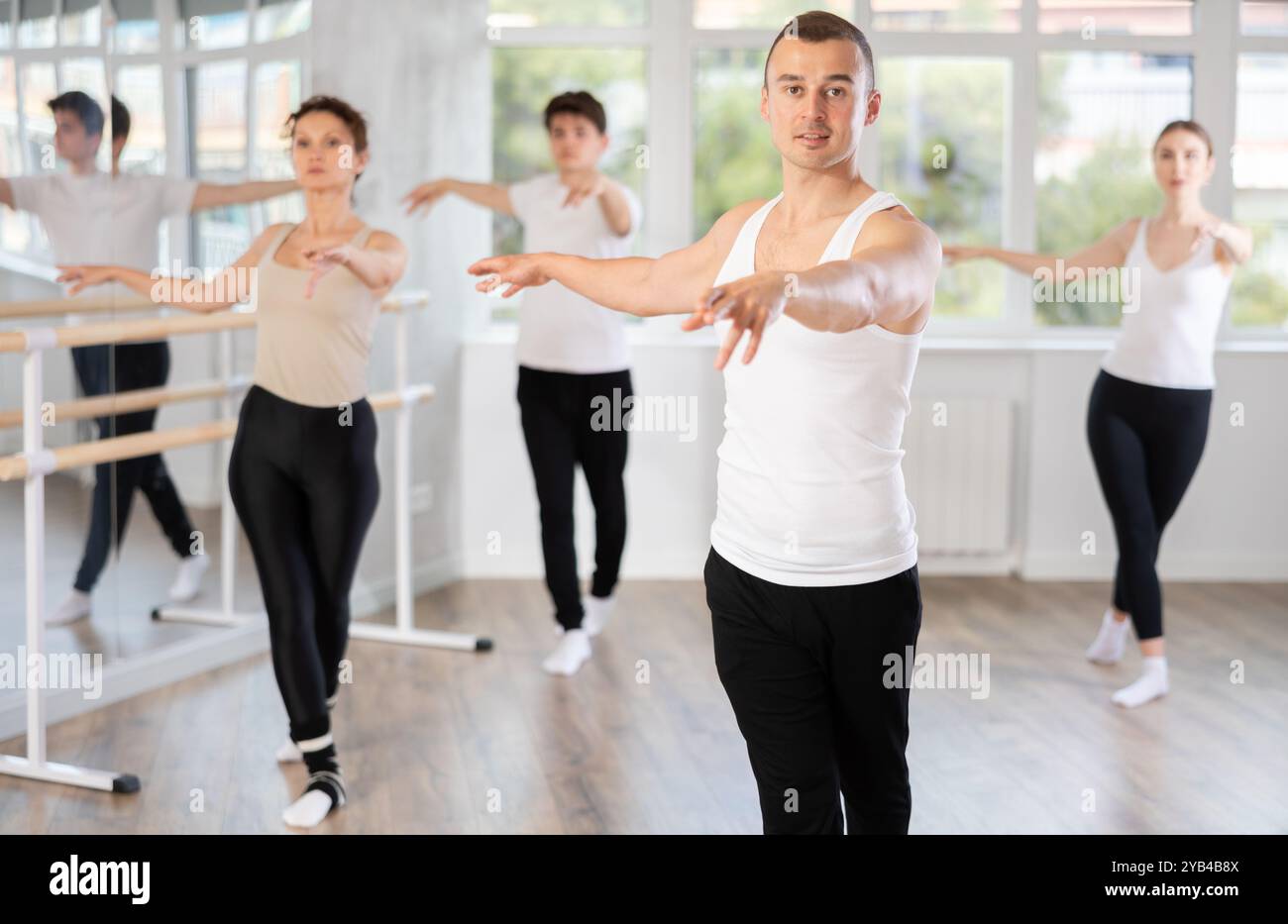 Happy young guy in sportswear confidently leading ballet class with ...