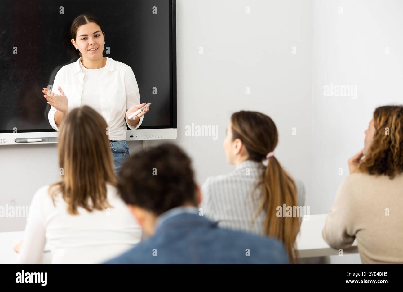 Positive female trainer standing near interactive board and conducting ...