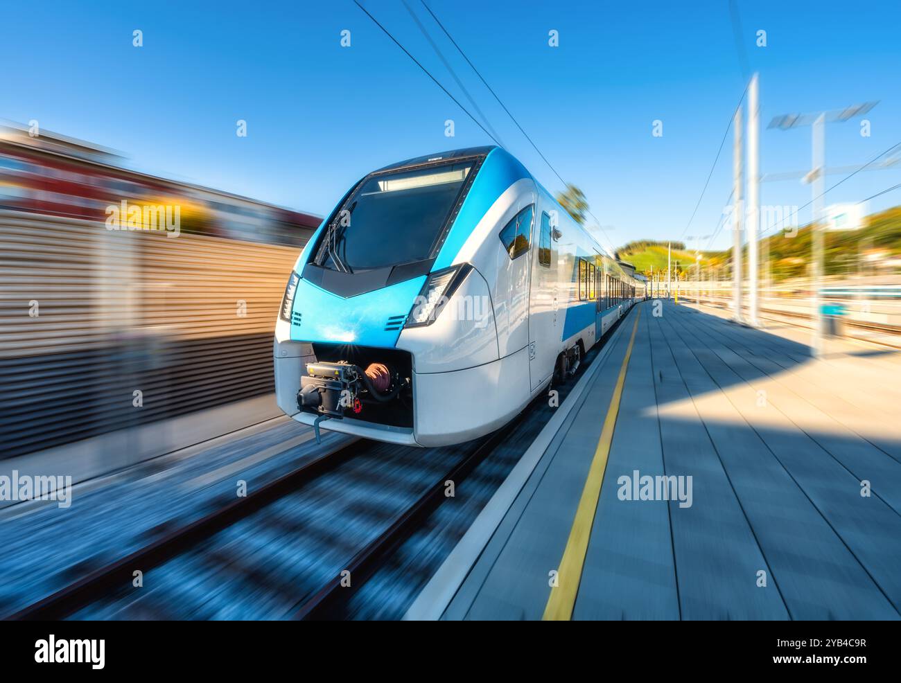 High-speed blue passenger train moving at railway station Stock Photo ...