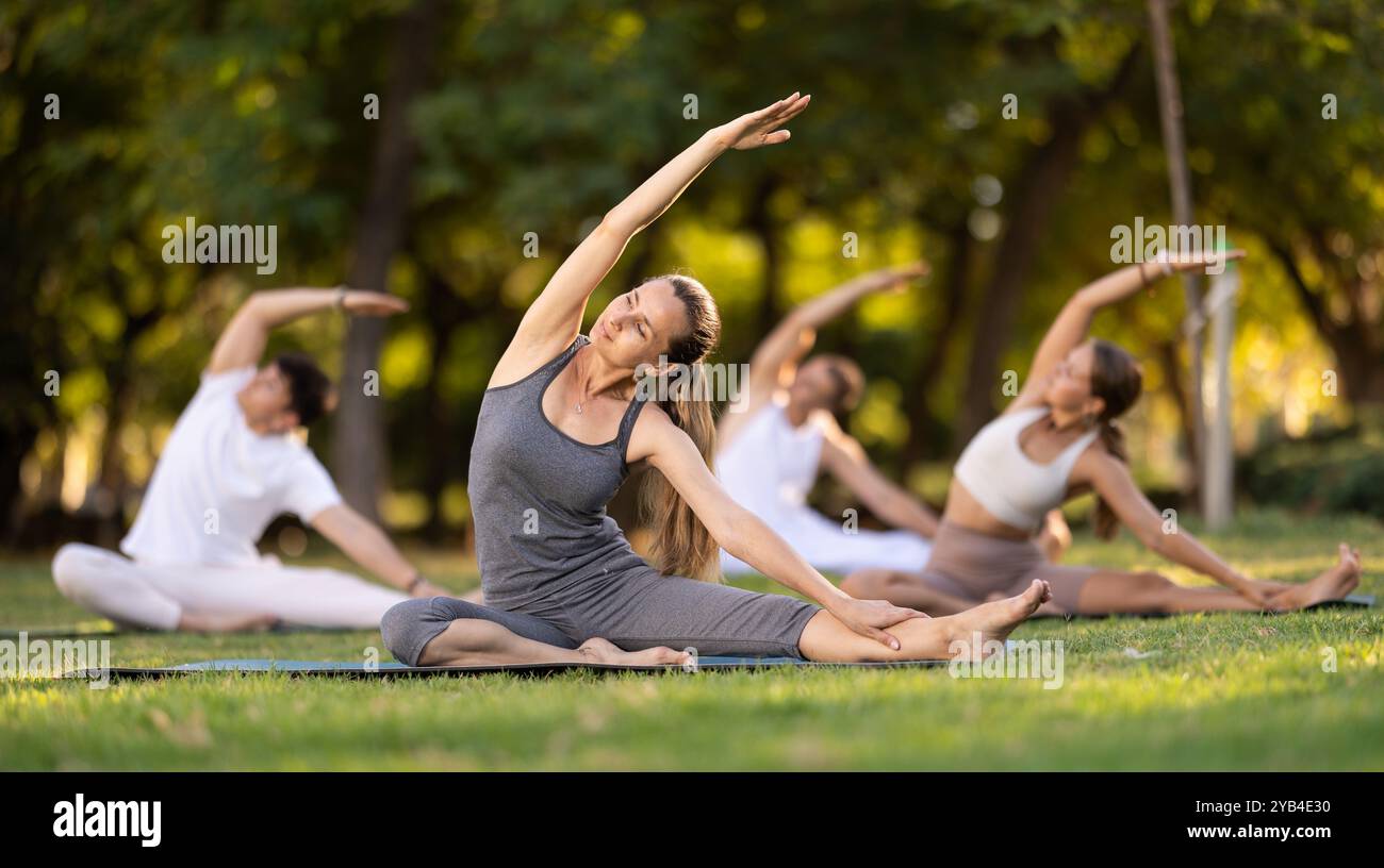 Woman performing yoga asanas during group session in park Stock Photo ...