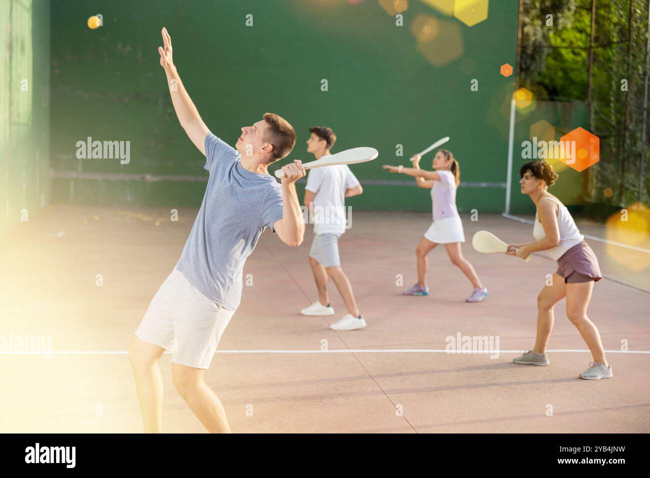 Guy playing pelota at open-air fronton, swinging wooden bat to return ball Stock Photo - Alamy