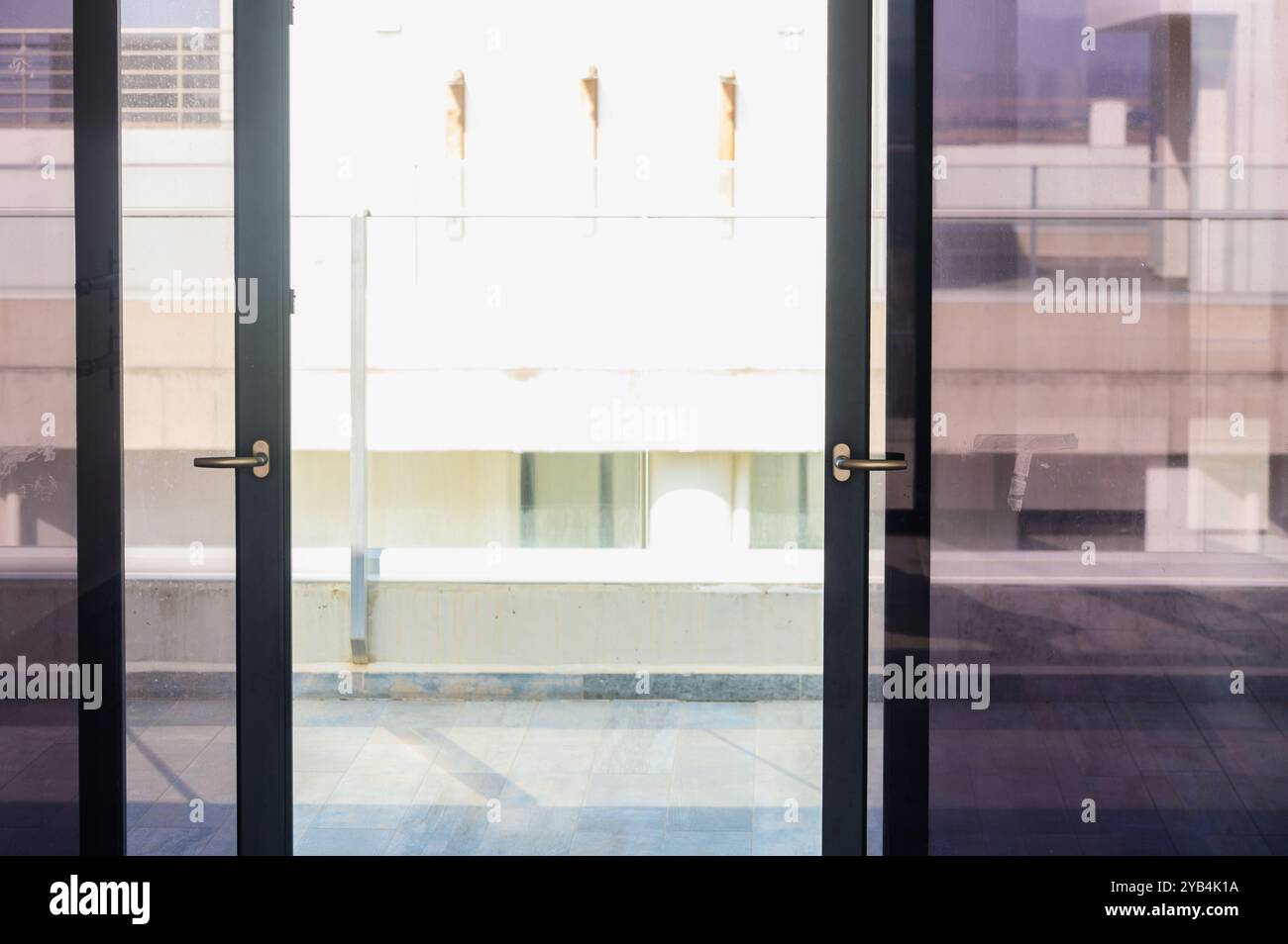 Sunlight pours through sleek glass doors revealing a modern urban ...