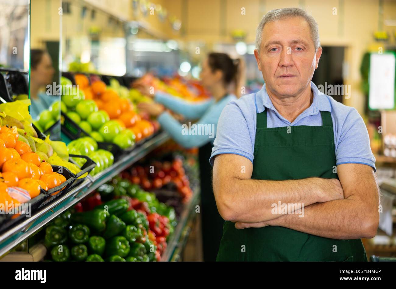 Portrait of confident mature male supermarket worker wearing apron ...