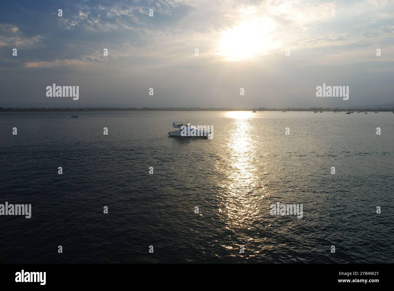 Boat gliding across tranquil water at sunset, leaving a wake under a ...