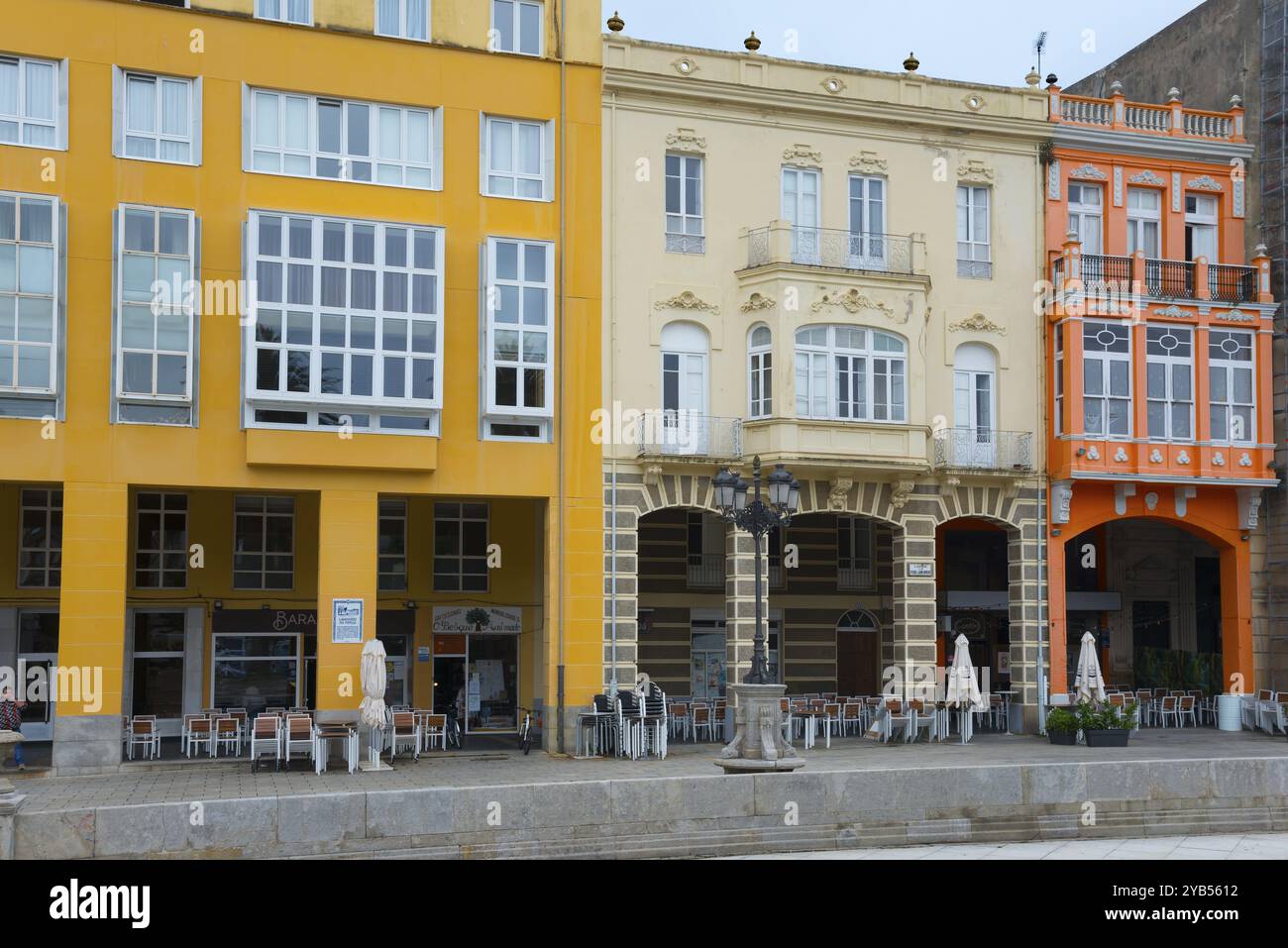 Three colourful buildings with elaborate facades and street cafes on ...