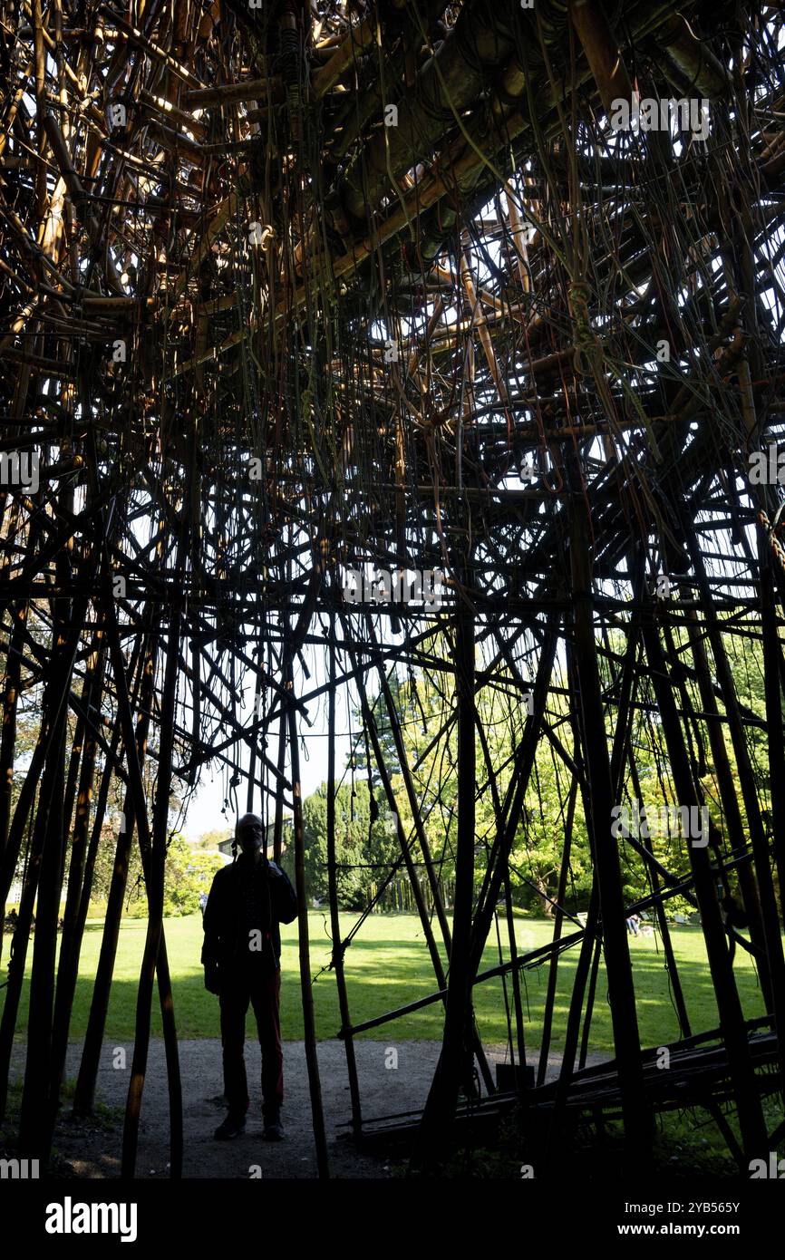 Visitors under a complex bamboo installation in the middle of a green ...