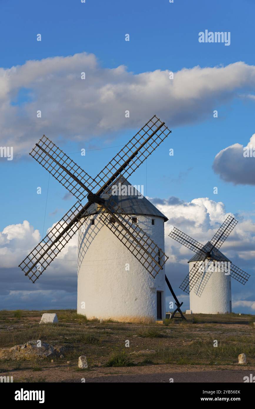 Two white windmills in a landscape under a blue sky and clouds in the ...