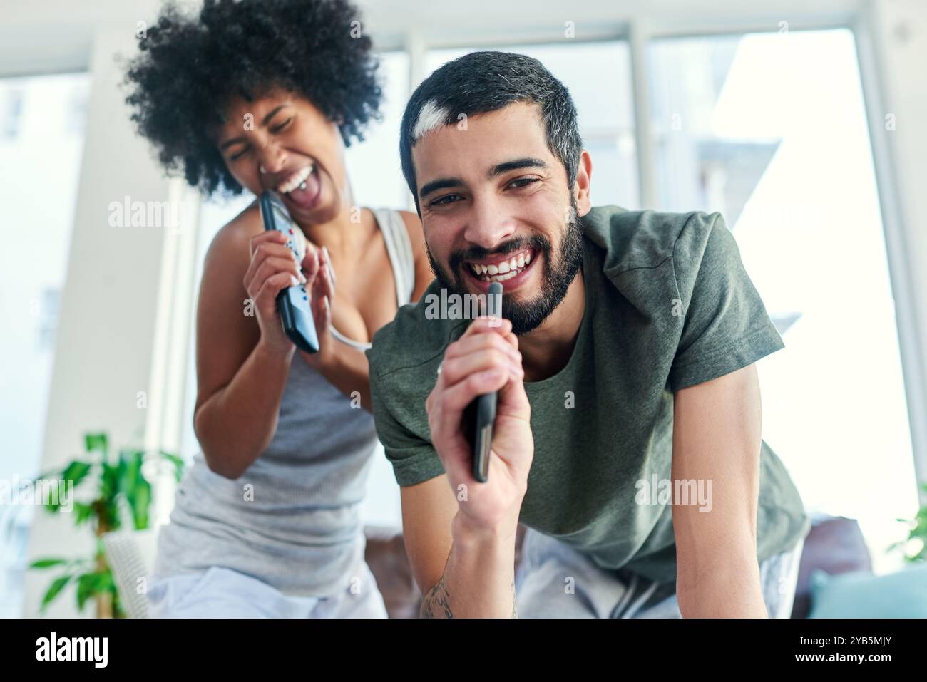 Couple, home and energy with singing in living room for music, fun or ...
