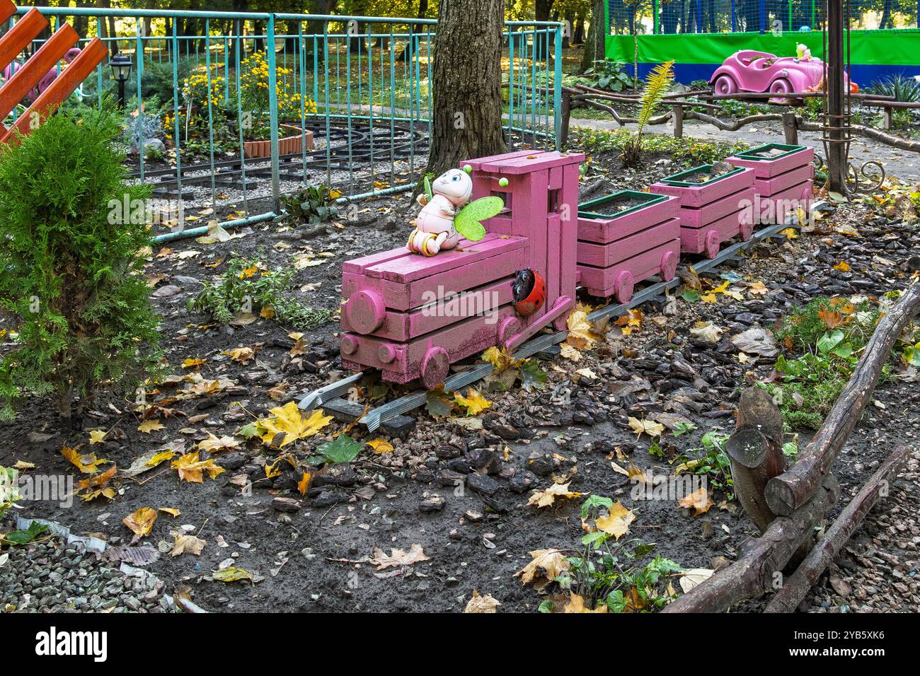 A charming pink wooden toy train stands in the garden of the park ...