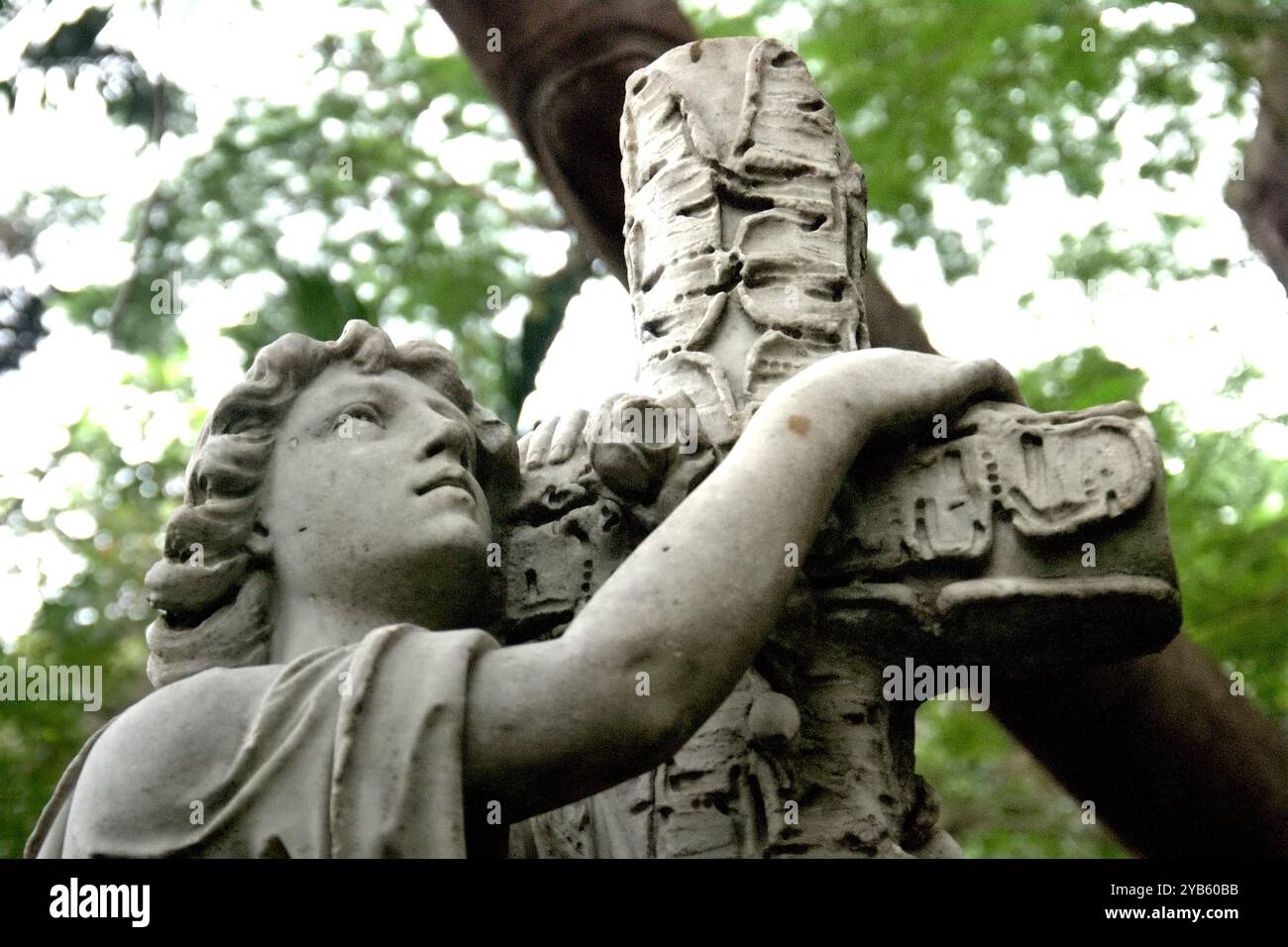 Statue of an angel figure holding a Christian cross at Taman Prasati ...