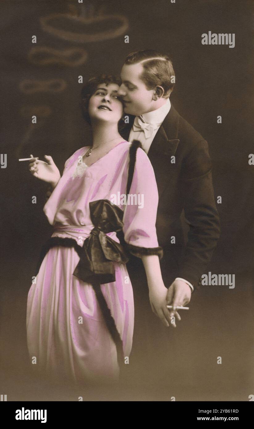 Vintage hand-coloured photograph of a romantic couple with cigarettes ...