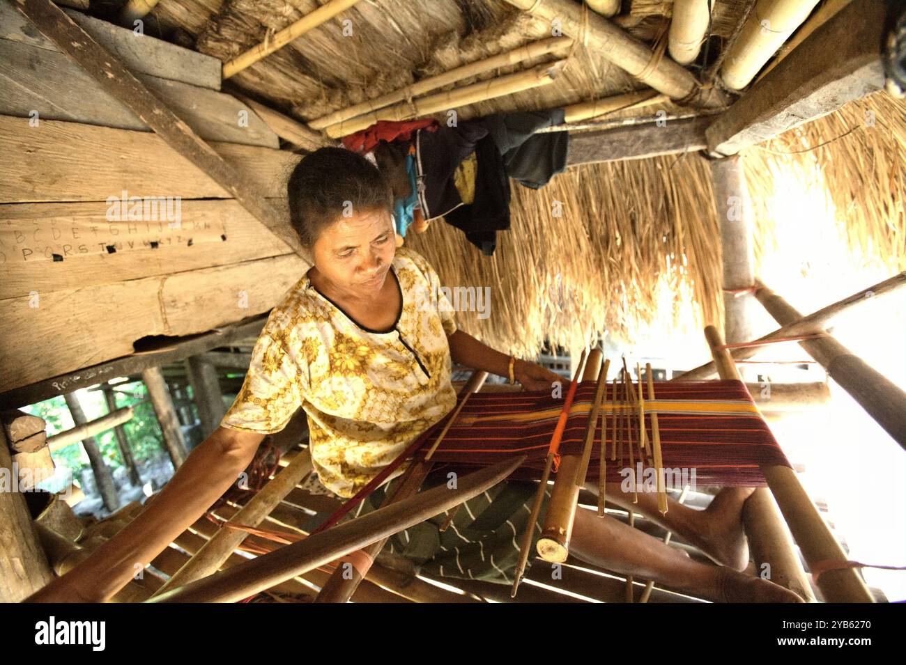 A woman weaving in a house in traditional village of Praijing in Tebara ...