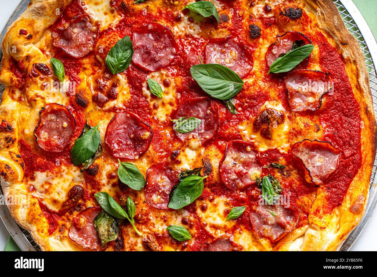 Pepperoni pizza close-up with basil on a metal circle, lattice ...