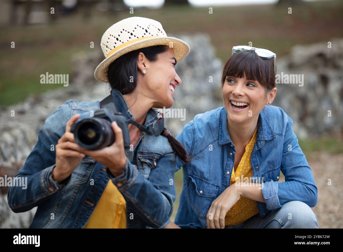 two women are laughing as they take photos outdoors Stock Photo - Alamy