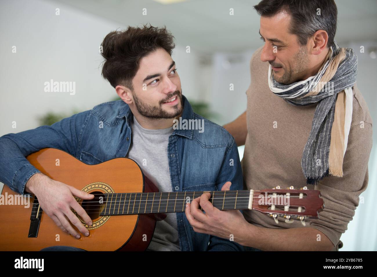man guiding student during guitar lesson Stock Photo - Alamy