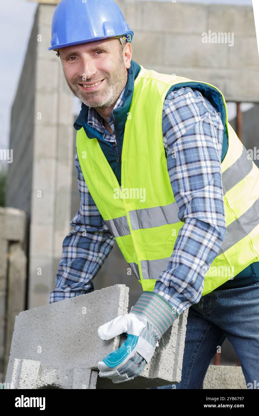 male worker carrying cement block Stock Photo - Alamy