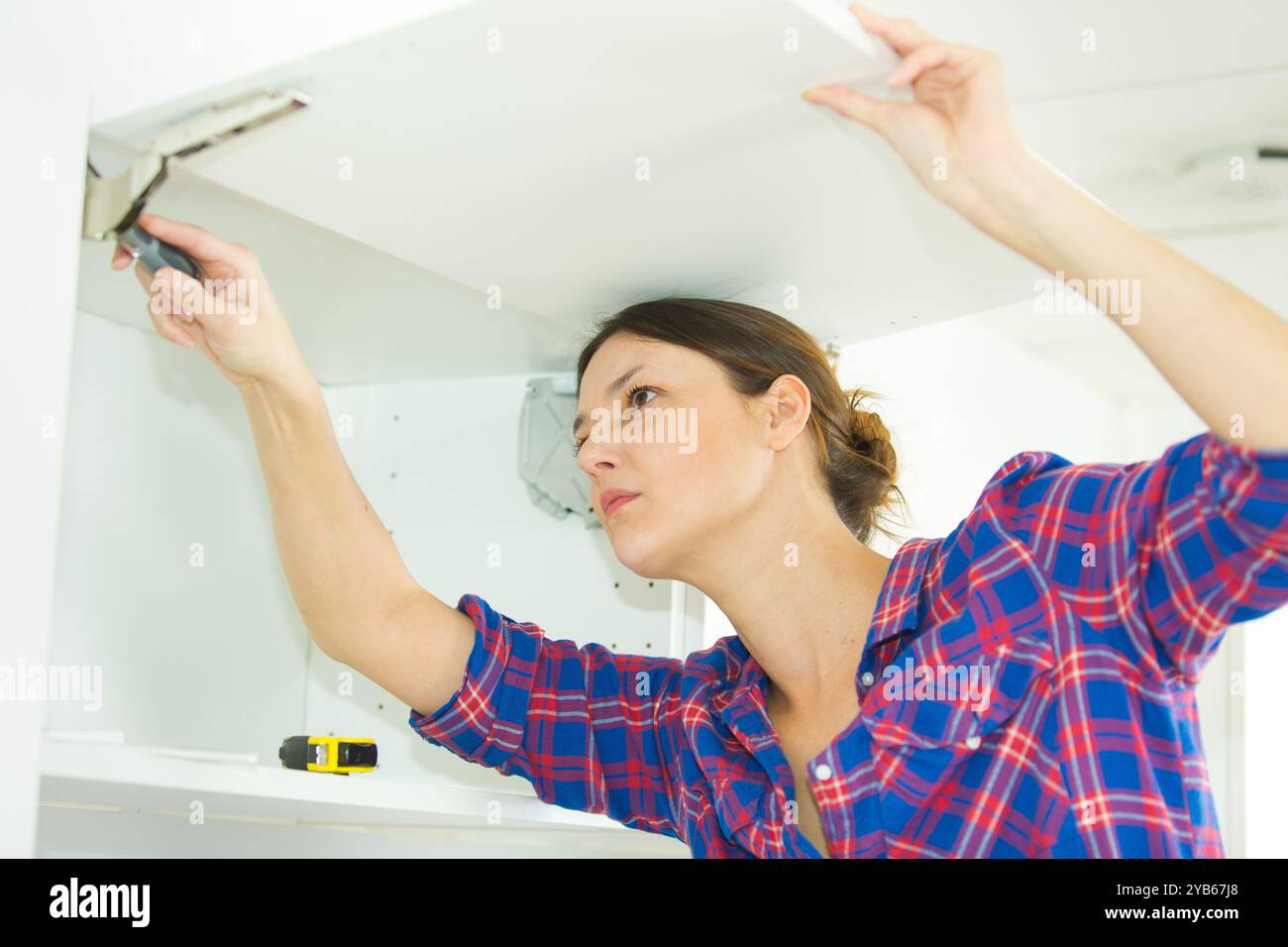 female handyman fixing cupboard hinge Stock Photo - Alamy
