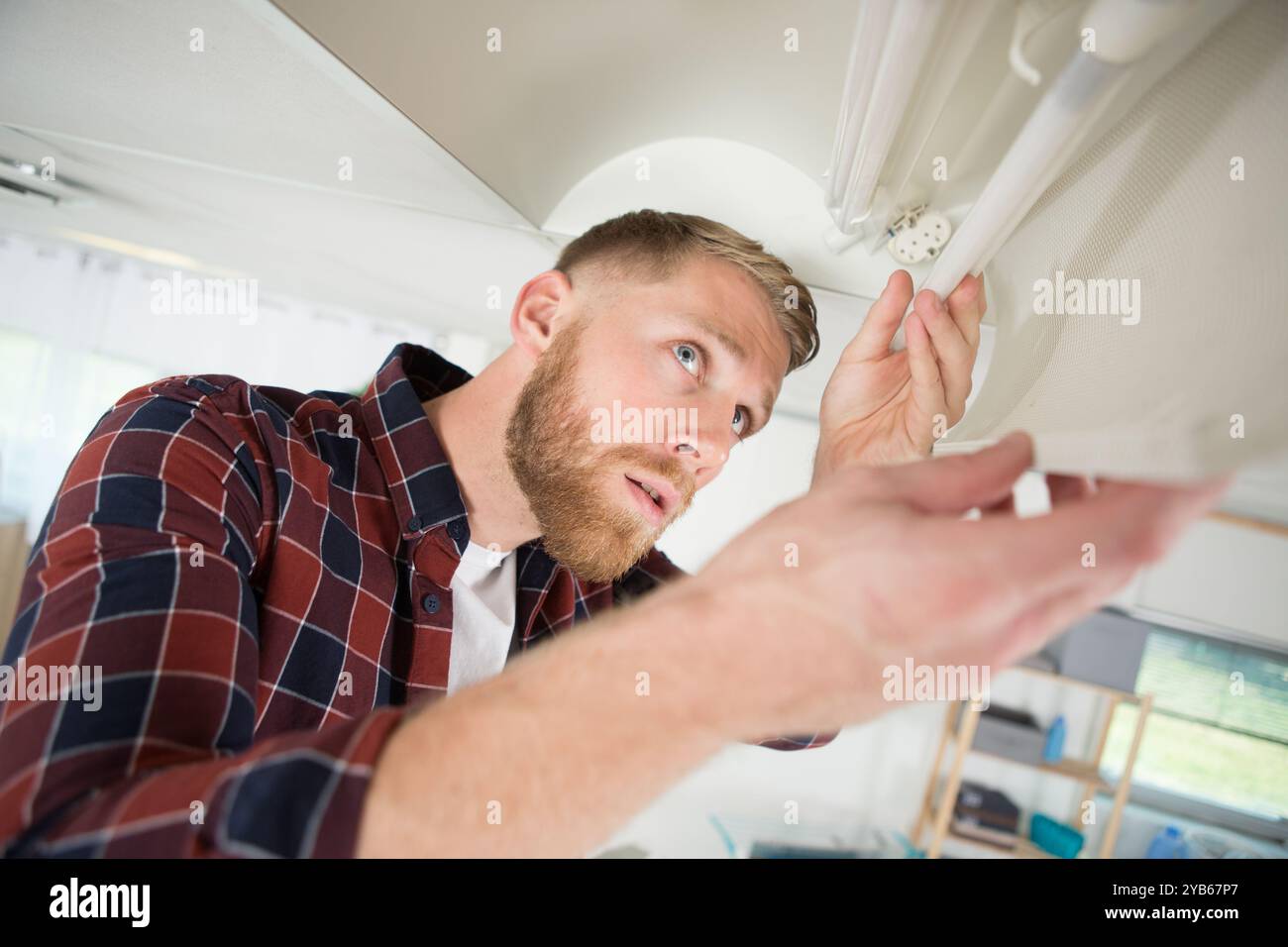 man installing a replacement fluorescent bulb Stock Photo - Alamy