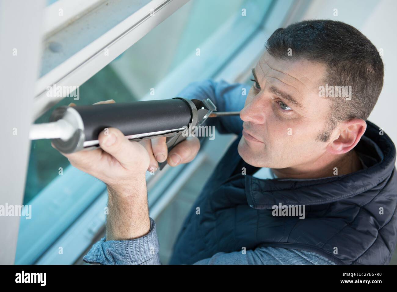 worker using silicone pistol on a windows Stock Photo - Alamy