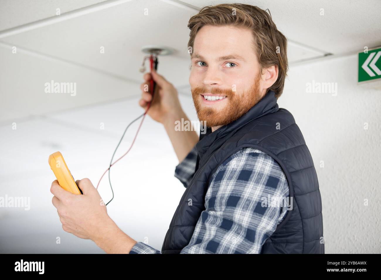 handsome electrician on stepladder installing lighting to the ceiling ...
