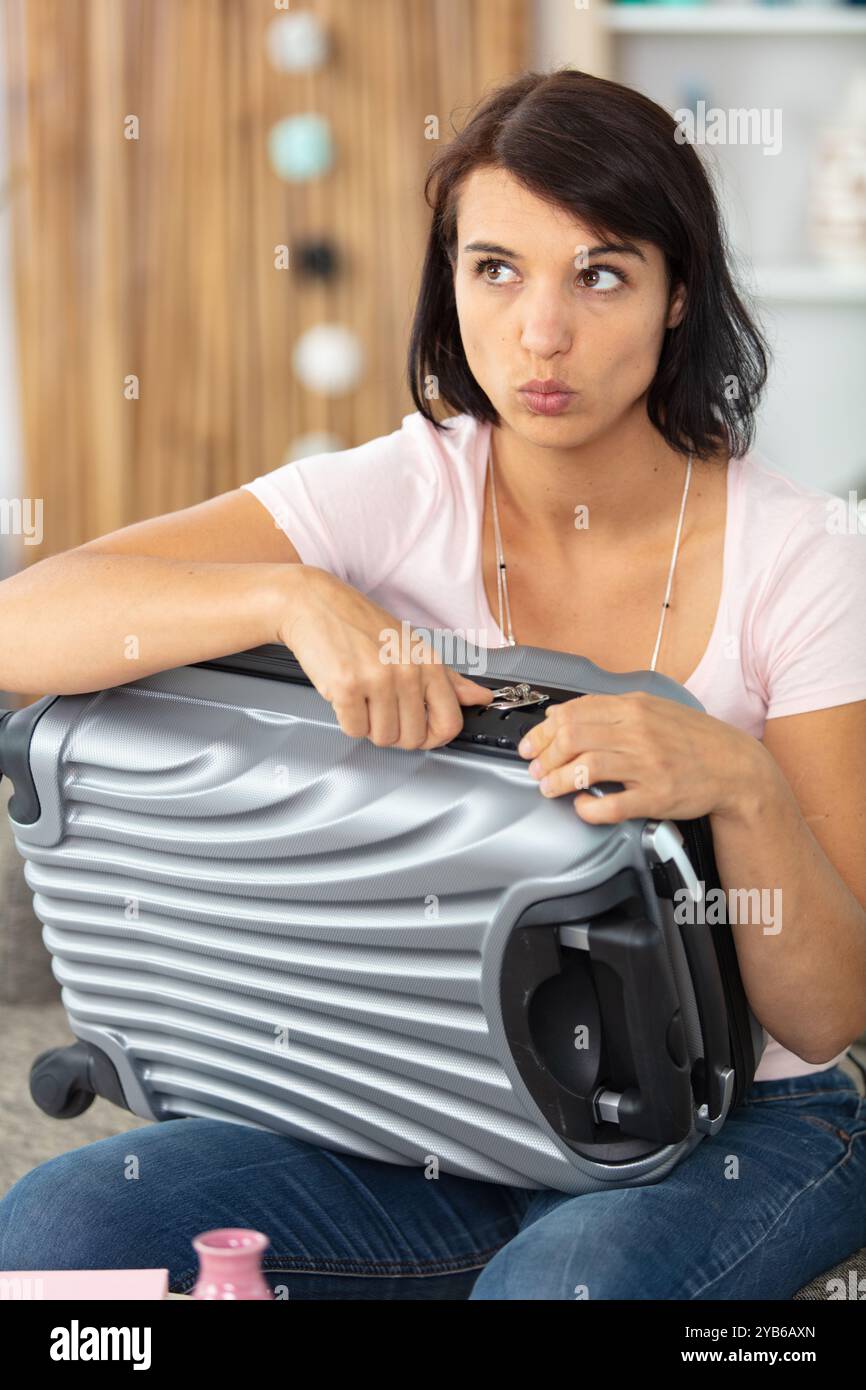 woman packing for vacation trying to close full suitcase Stock Photo - Alamy
