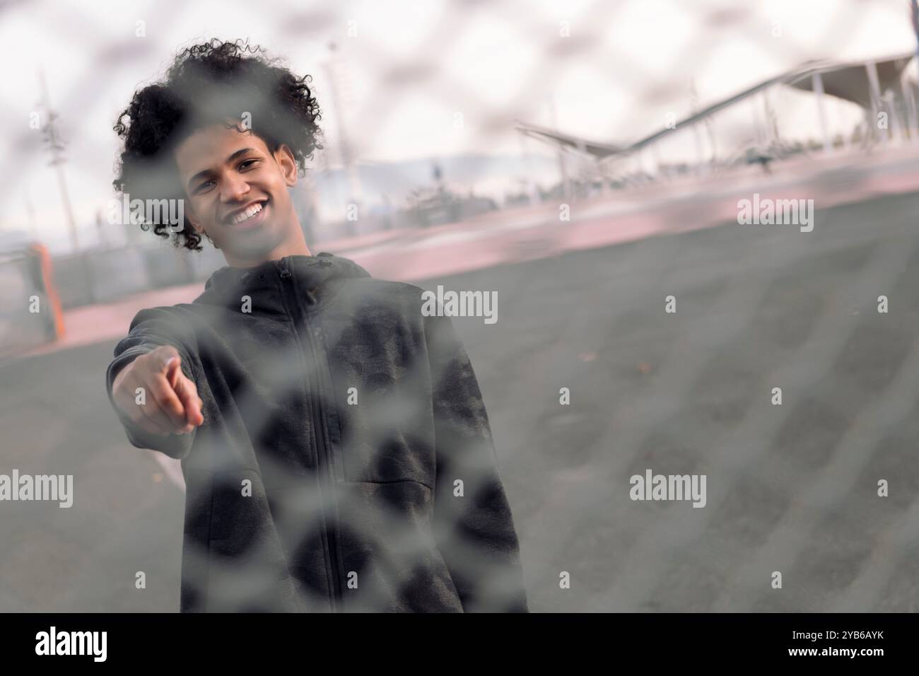 teen with curly hair behind metal chain link fence Stock Photo - Alamy