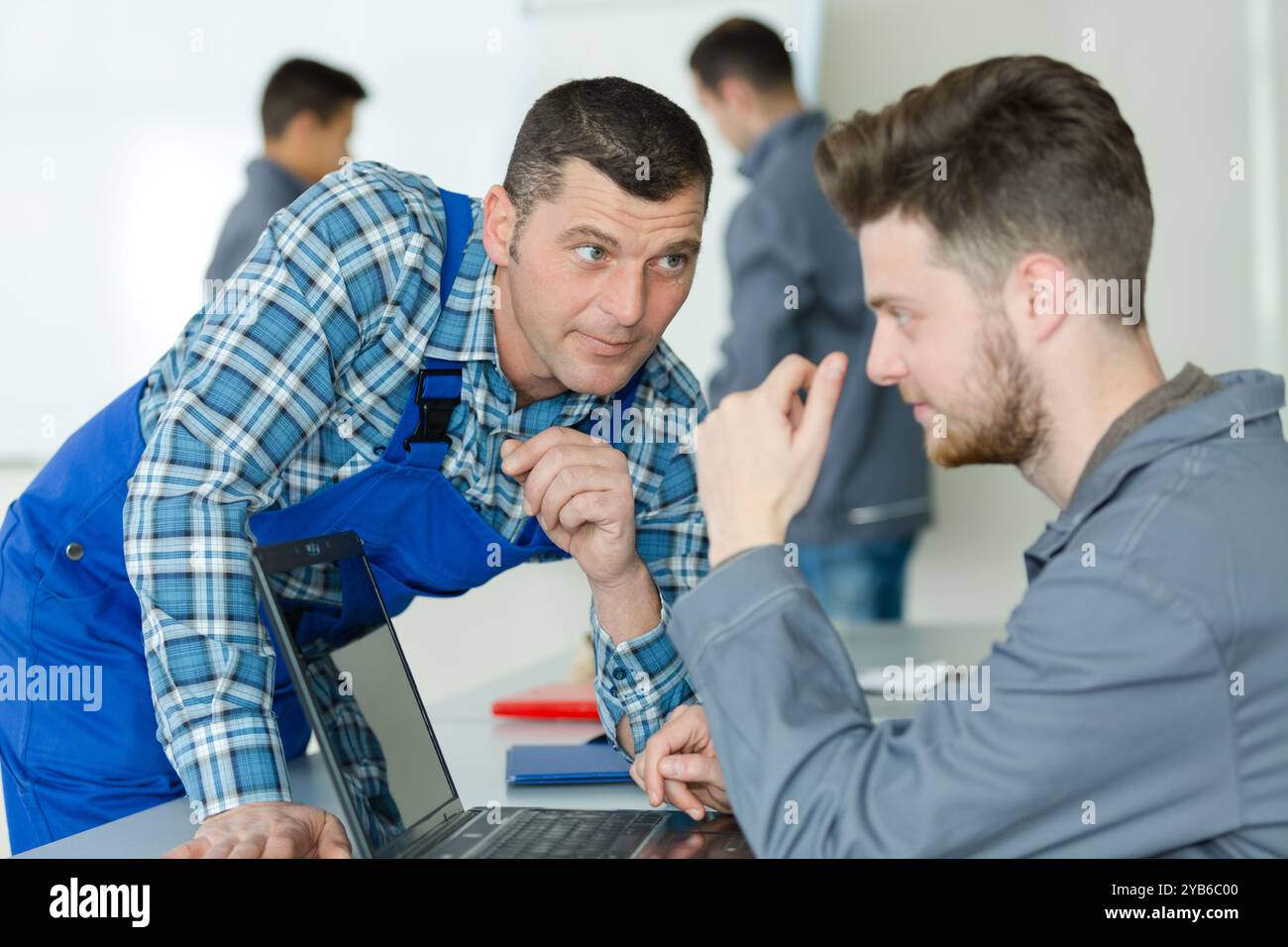 teacher questioning male teenage student using laptop computer Stock ...