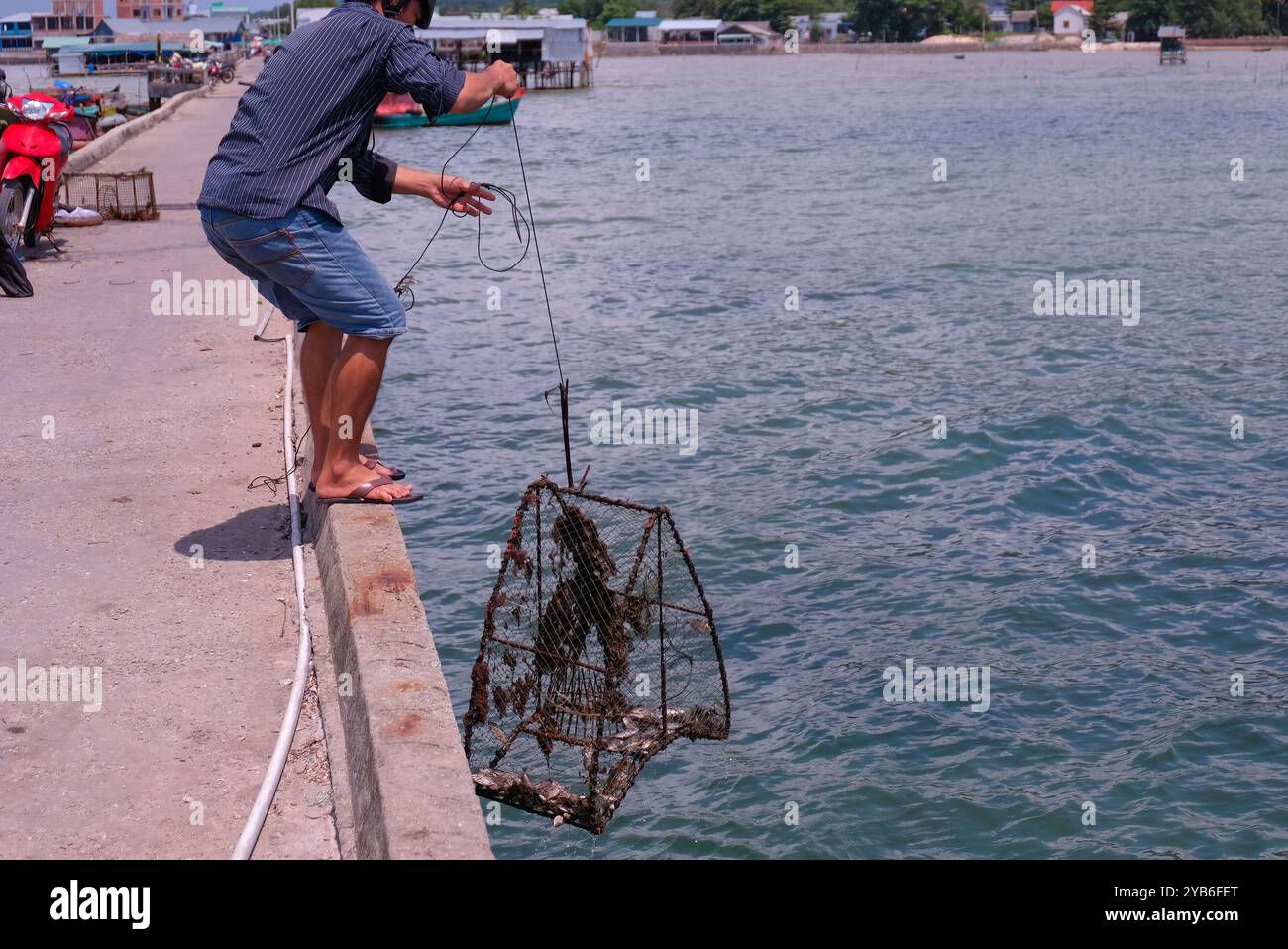Phu Quoc, Vietnam 2018 May17 - Local man retrieves metal fishing cage ...