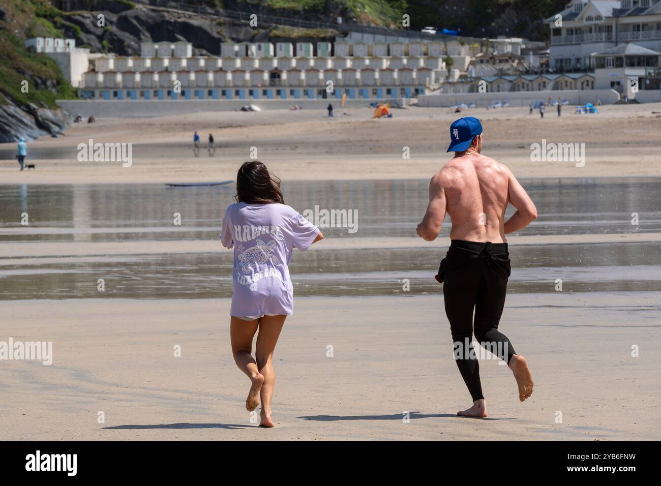 Two holidaymakers people running along Tolcarne Beach in Newquay in ...