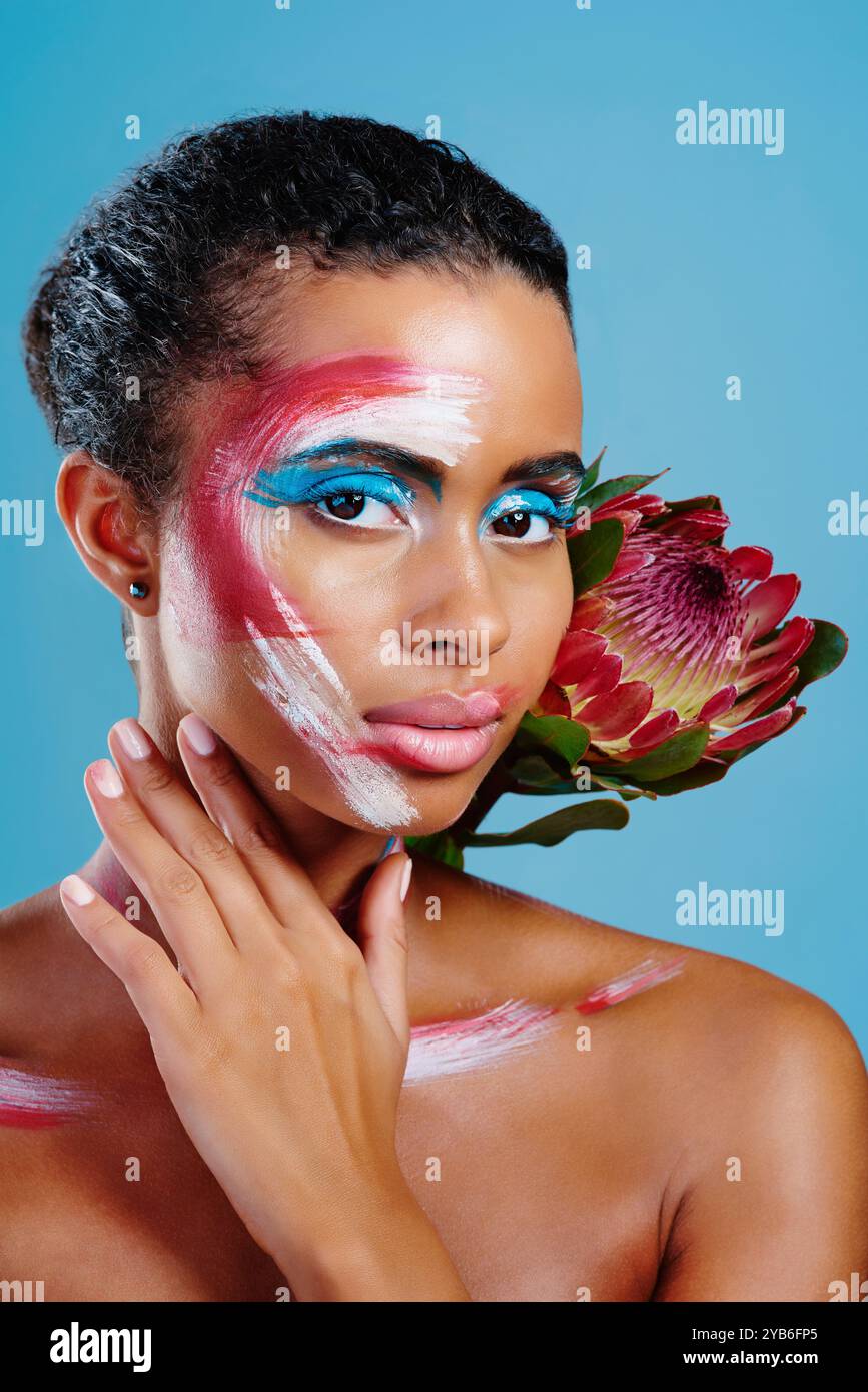 Studio, creative and woman with face paint, flower and color of makeup ...