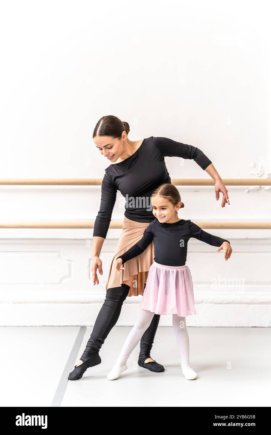Happy ballerina teacher guiding young student in graceful ballet ...