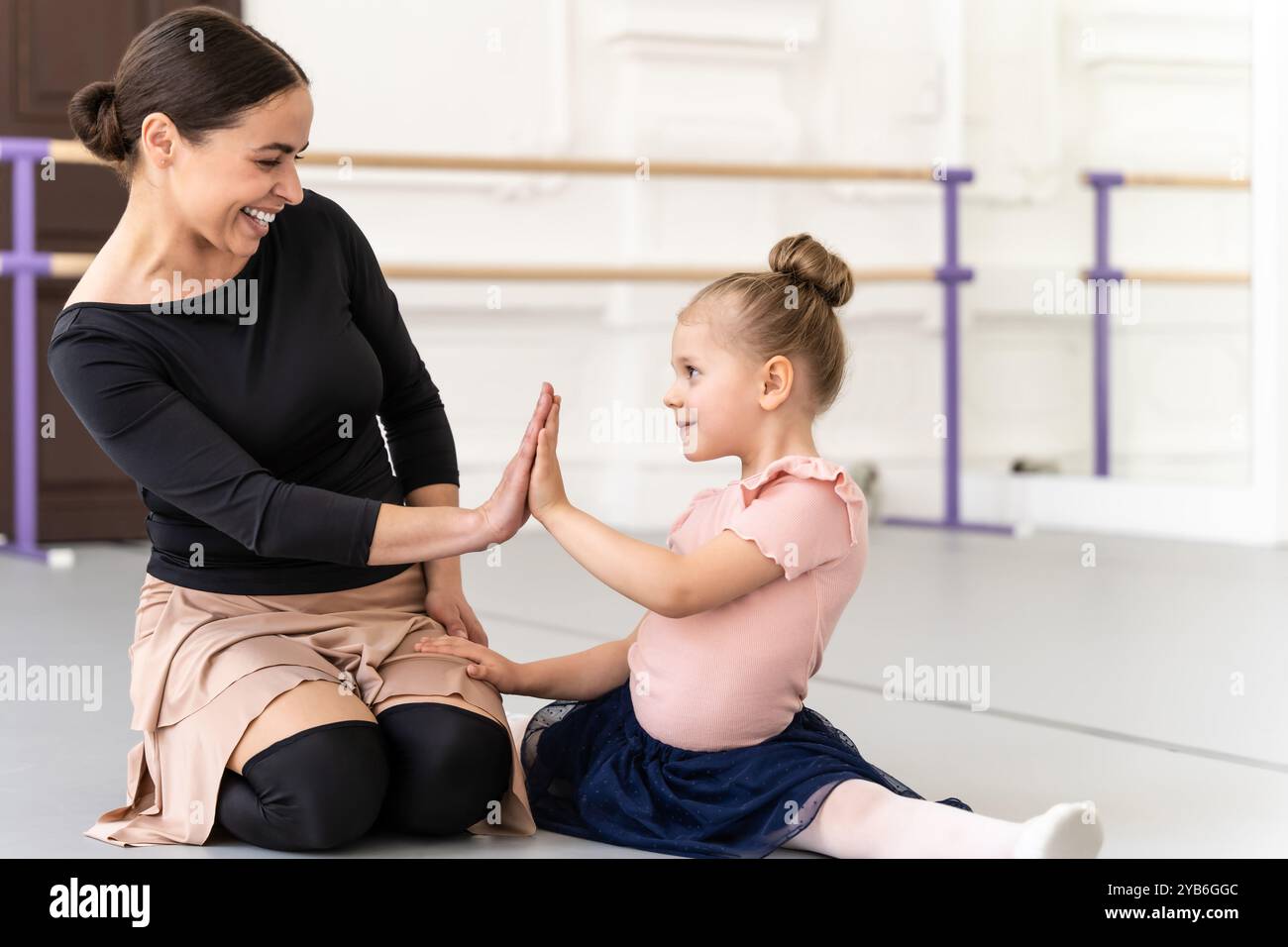 Female ballet coach giving high five to her pupil indoors after ...