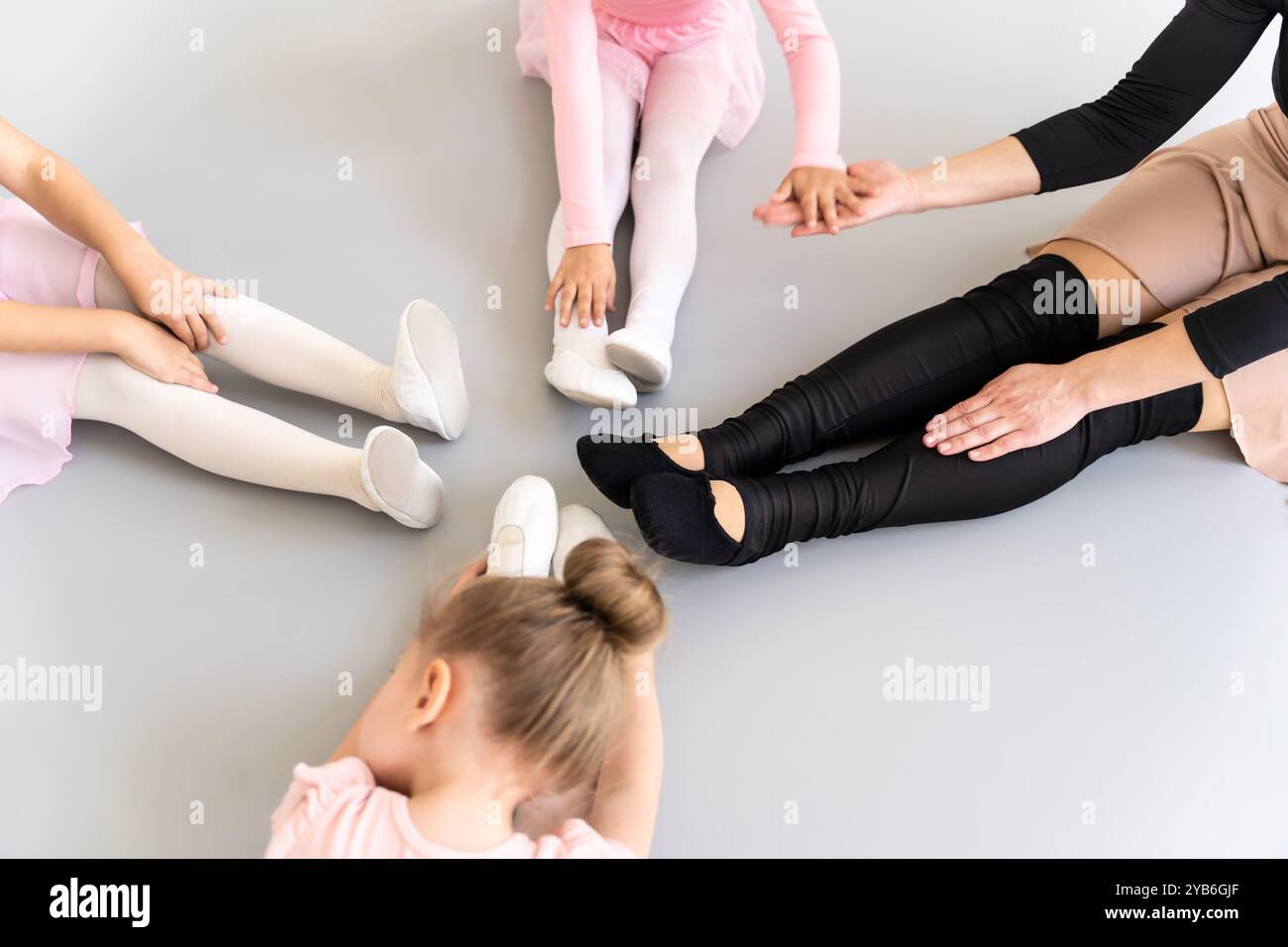 Ballet dancers wearing pointe shoes sitting in floor stretching during classical choreography ...