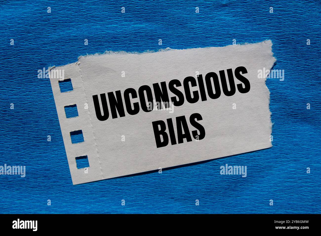 Unconscious bias message written on ripped torn paper piece with blue background. Conceptual ...