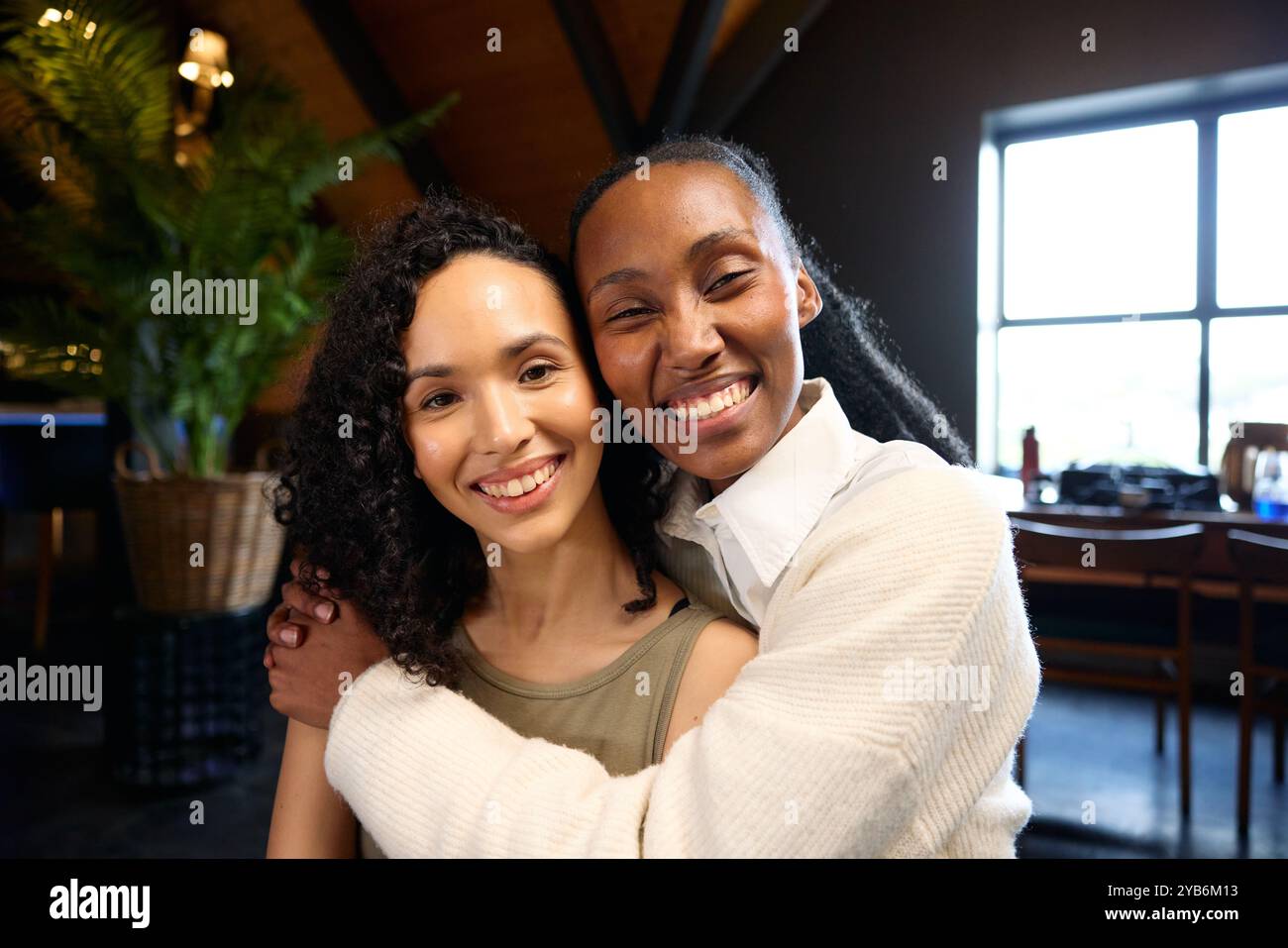 A African woman hugging her Caucasian friend from behind Stock Photo ...