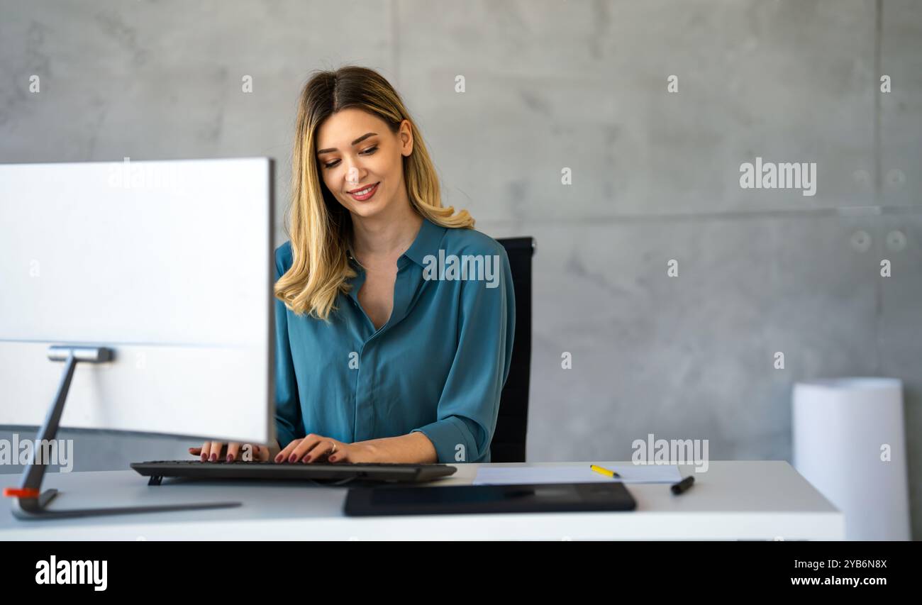 Young happy successful business woman working with computer in ...