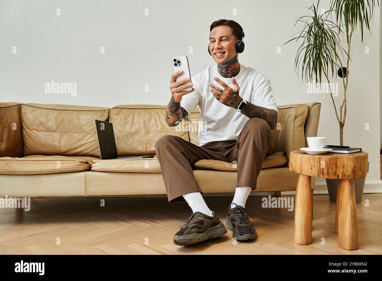 A stylish young man lounges at home, engaged in a cheerful video call ...