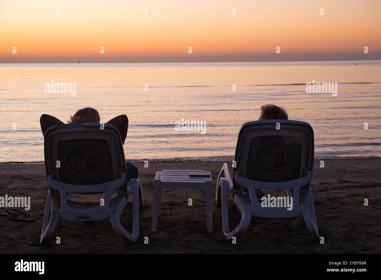 Couple sitting waiting for sunrise on Finikoudes beach in Cyprus Stock ...